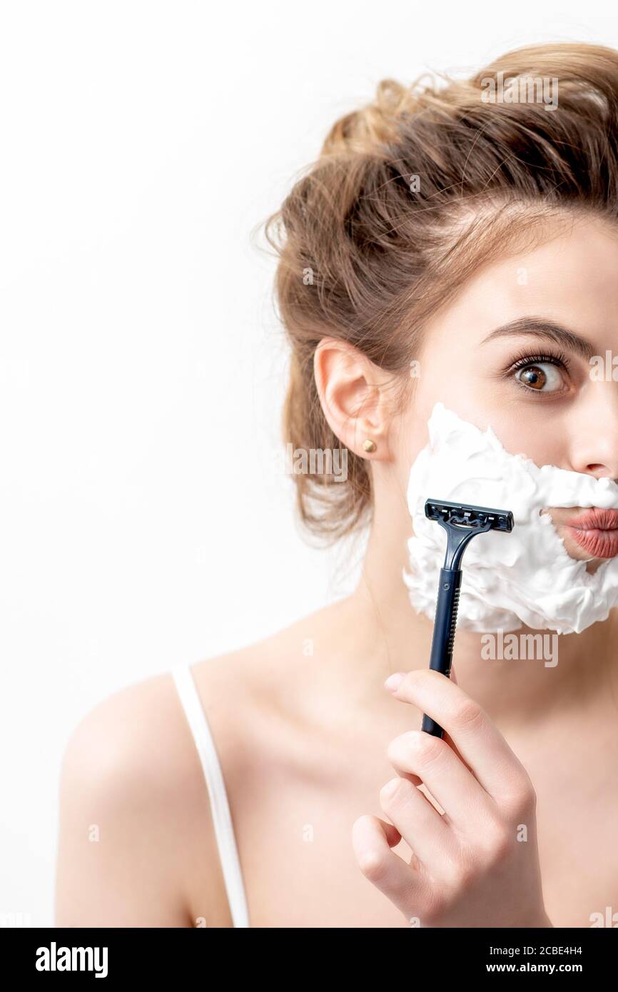 Beautiful young caucasian woman shaving her face by razor on white ...