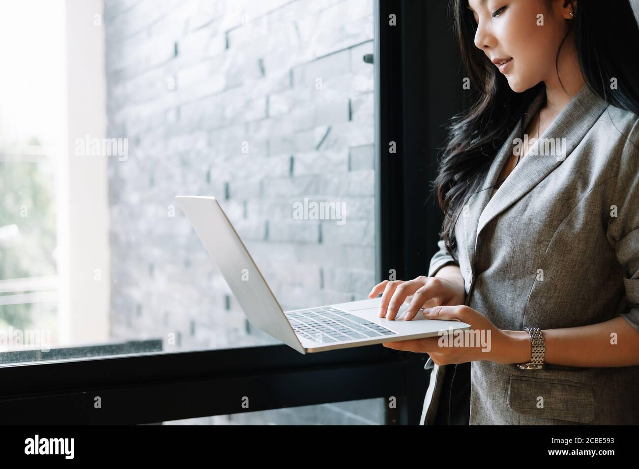 Portrait of smiling millennial businesswoman holding laptop computer ...