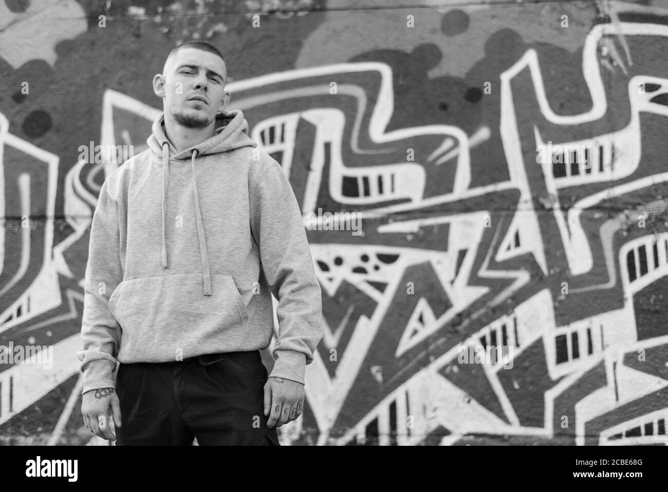 A bully guy in a light sports jacket with a hood. Black and white photo ...