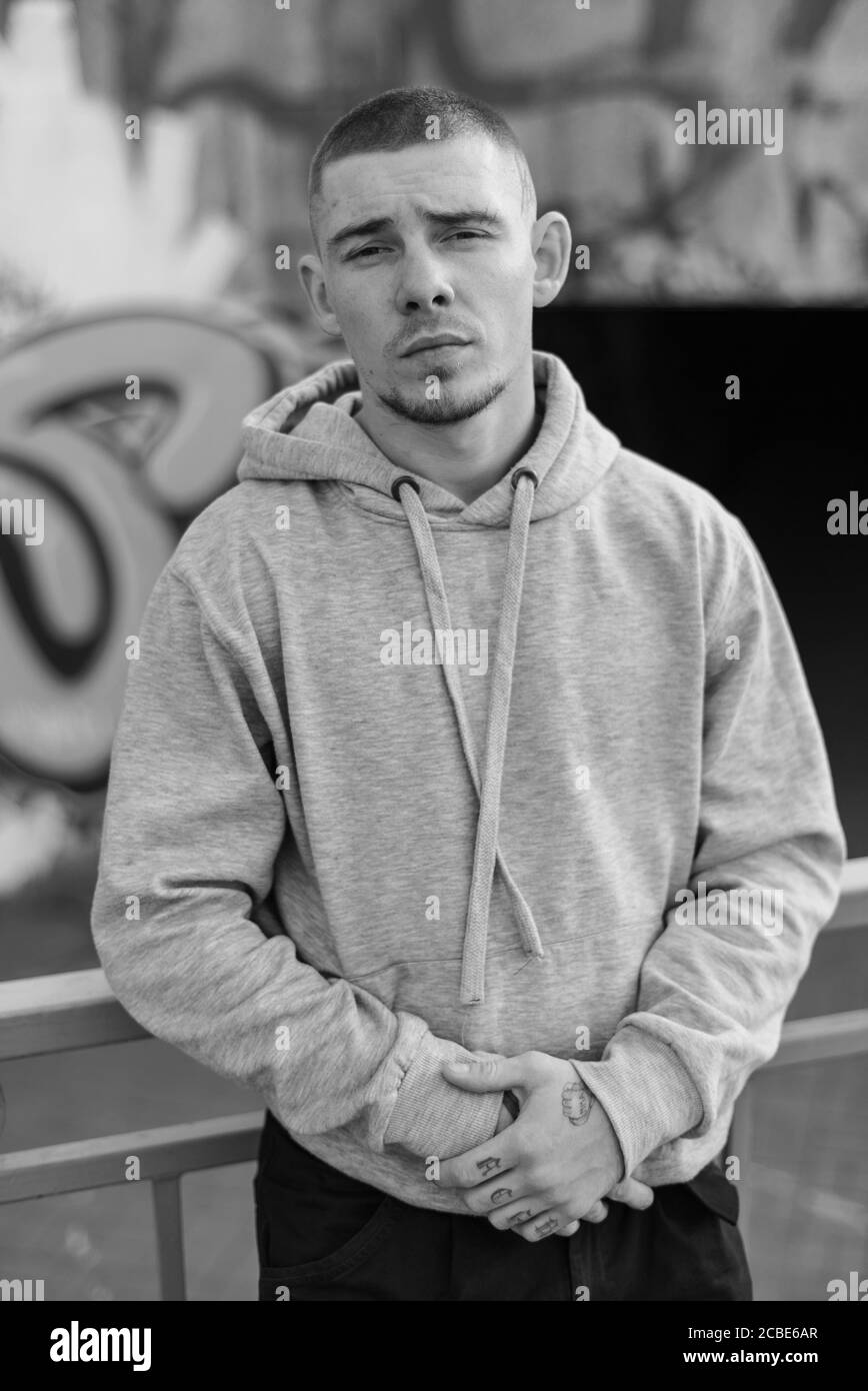 A bully guy in a light sports jacket with a hood. Black and white photo ...