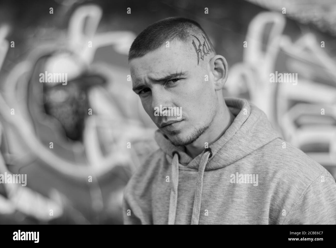 A bully guy in a light sports jacket with a hood. Black and white photo ...