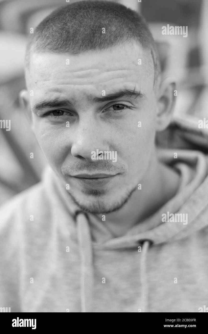 A bully guy in a light sports jacket with a hood. Black and white photo ...