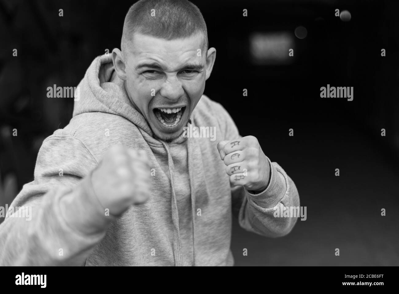 A bully guy in a light sports jacket with a hood. Black and white photo ...