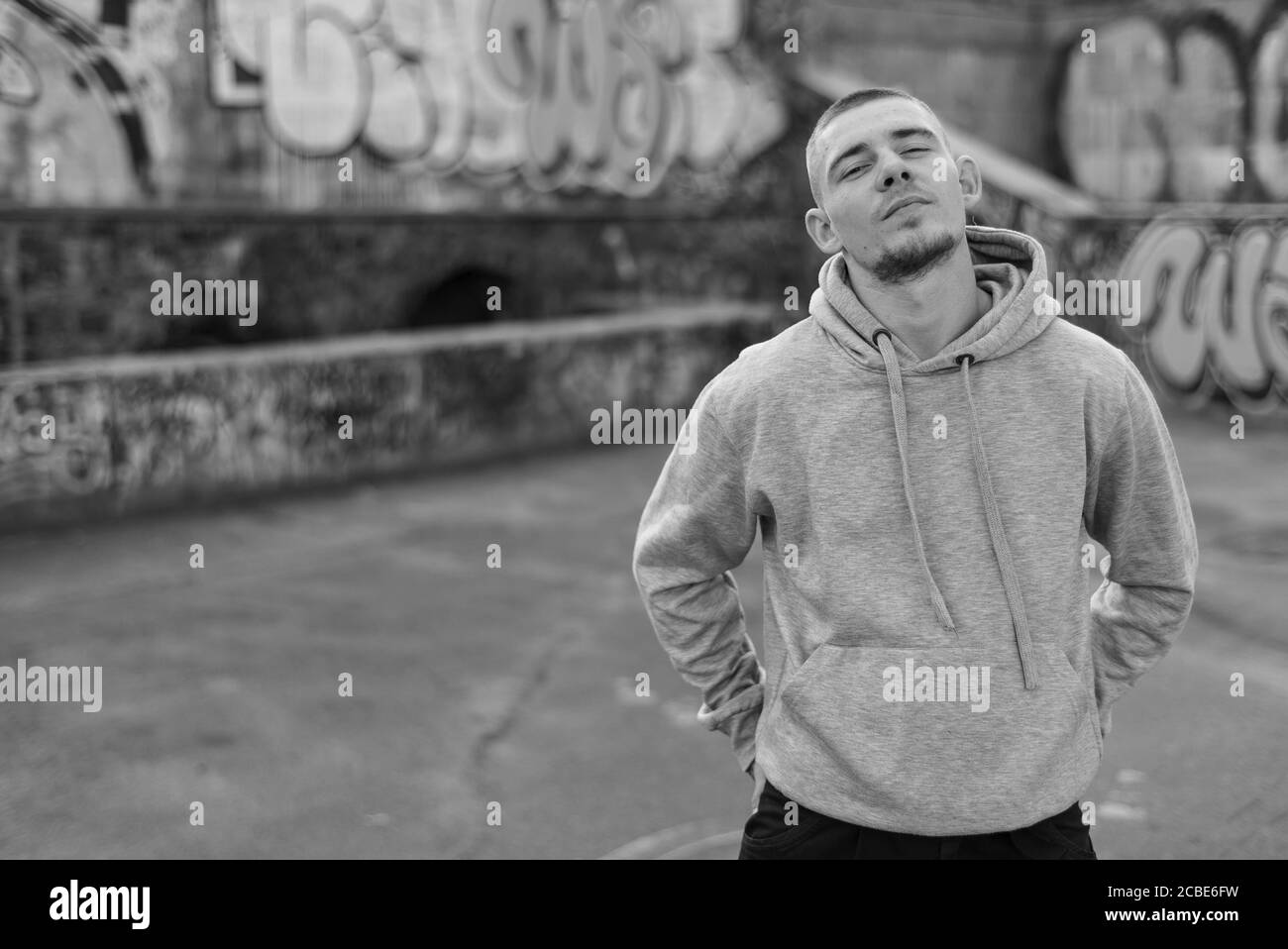A bully guy in a light sports jacket with a hood. Black and white photo ...
