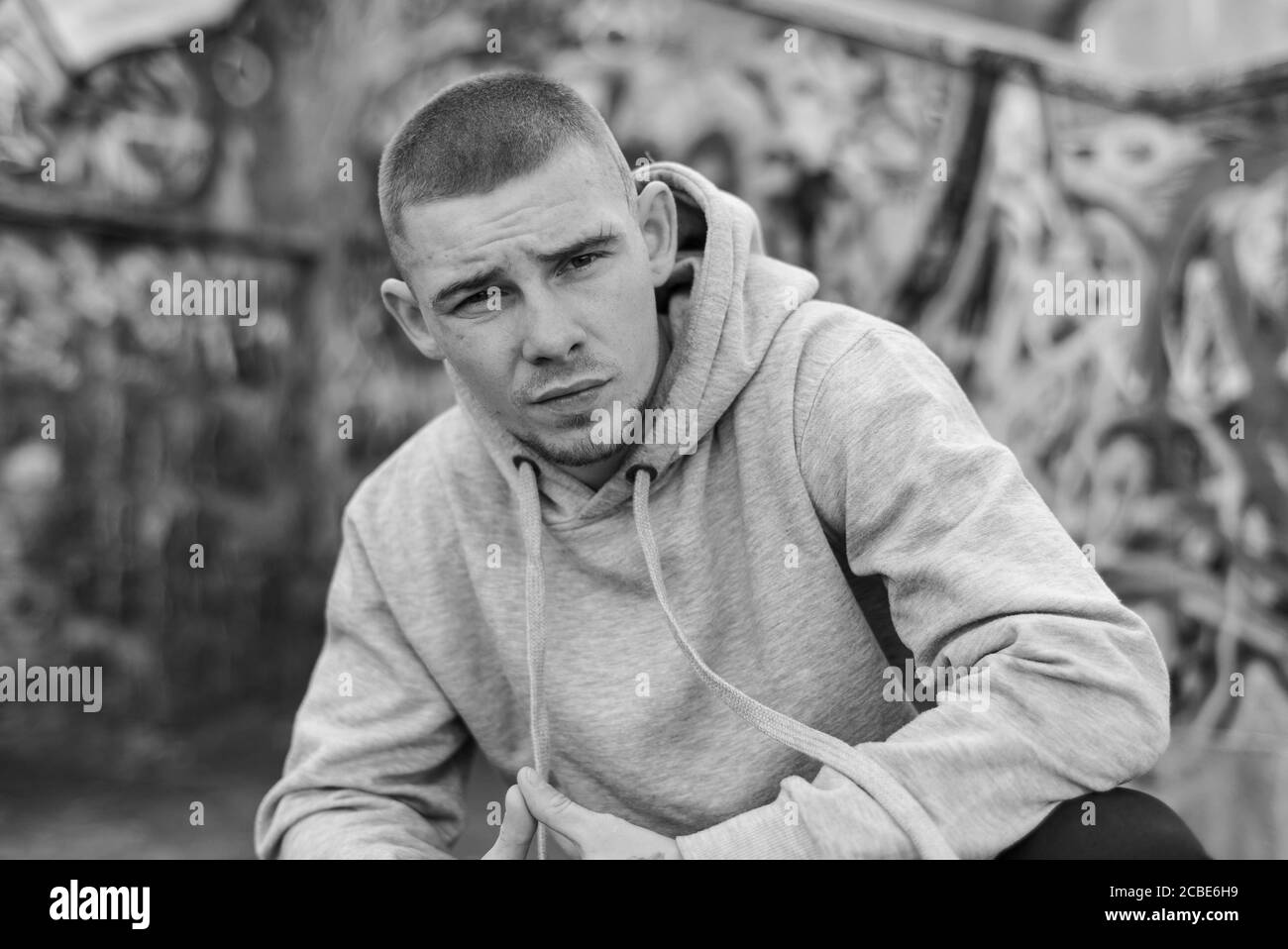 A bully guy in a light sports jacket with a hood. Black and white photo ...