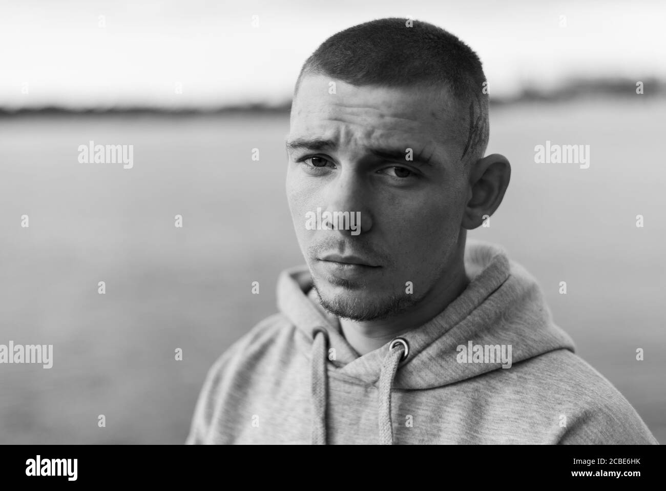 A bully guy in a light sports jacket with a hood. Black and white photo ...