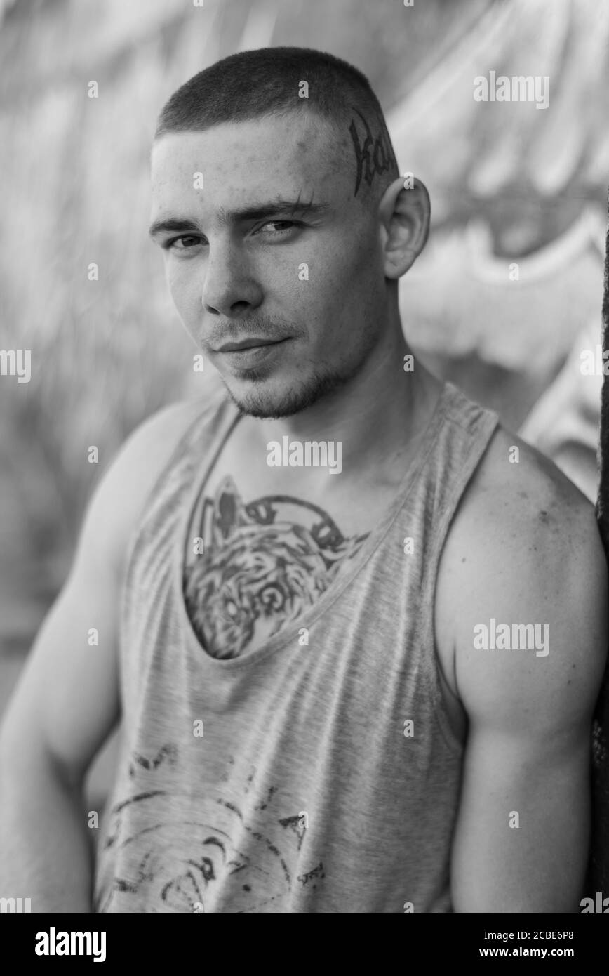 A bully guy in a sports shirt near a wall with graffiti. Black and ...
