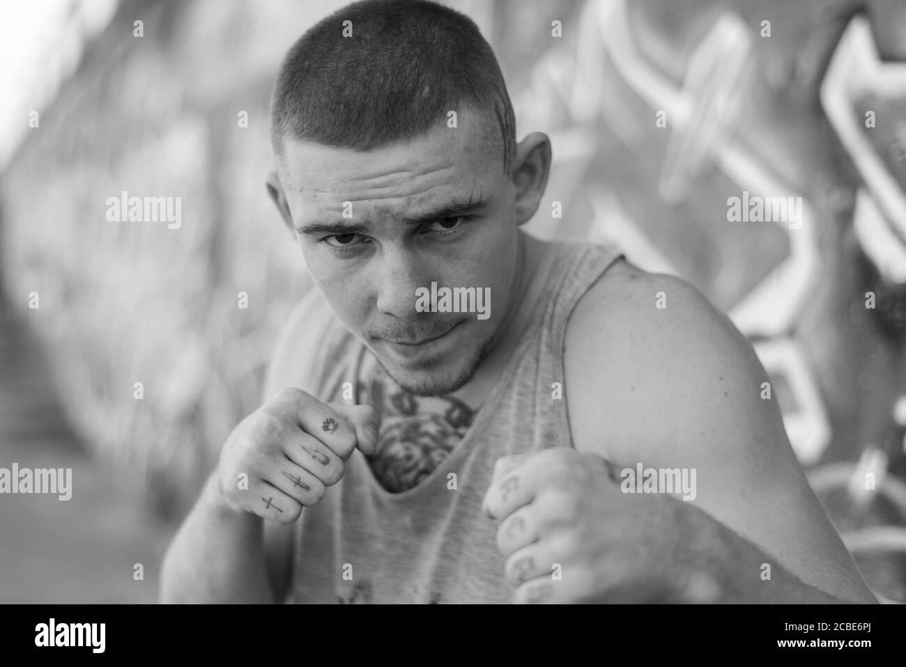 A bully guy in a sports shirt near a wall with graffiti. Black and ...