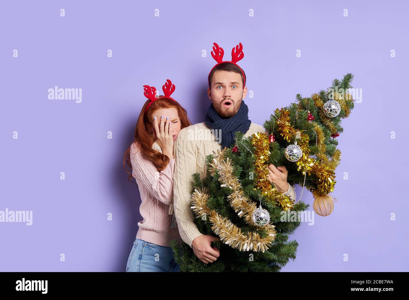 Young Fearful couple standing with shocked faces, woman with her hair ...