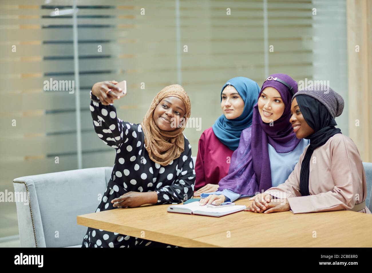 Four asian Muslim student girls sitting together, wearing hijabs and ...