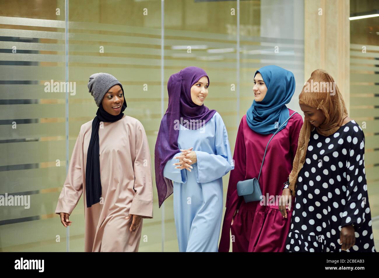A group of four young islamic multiethnic girls chatting and walking ...