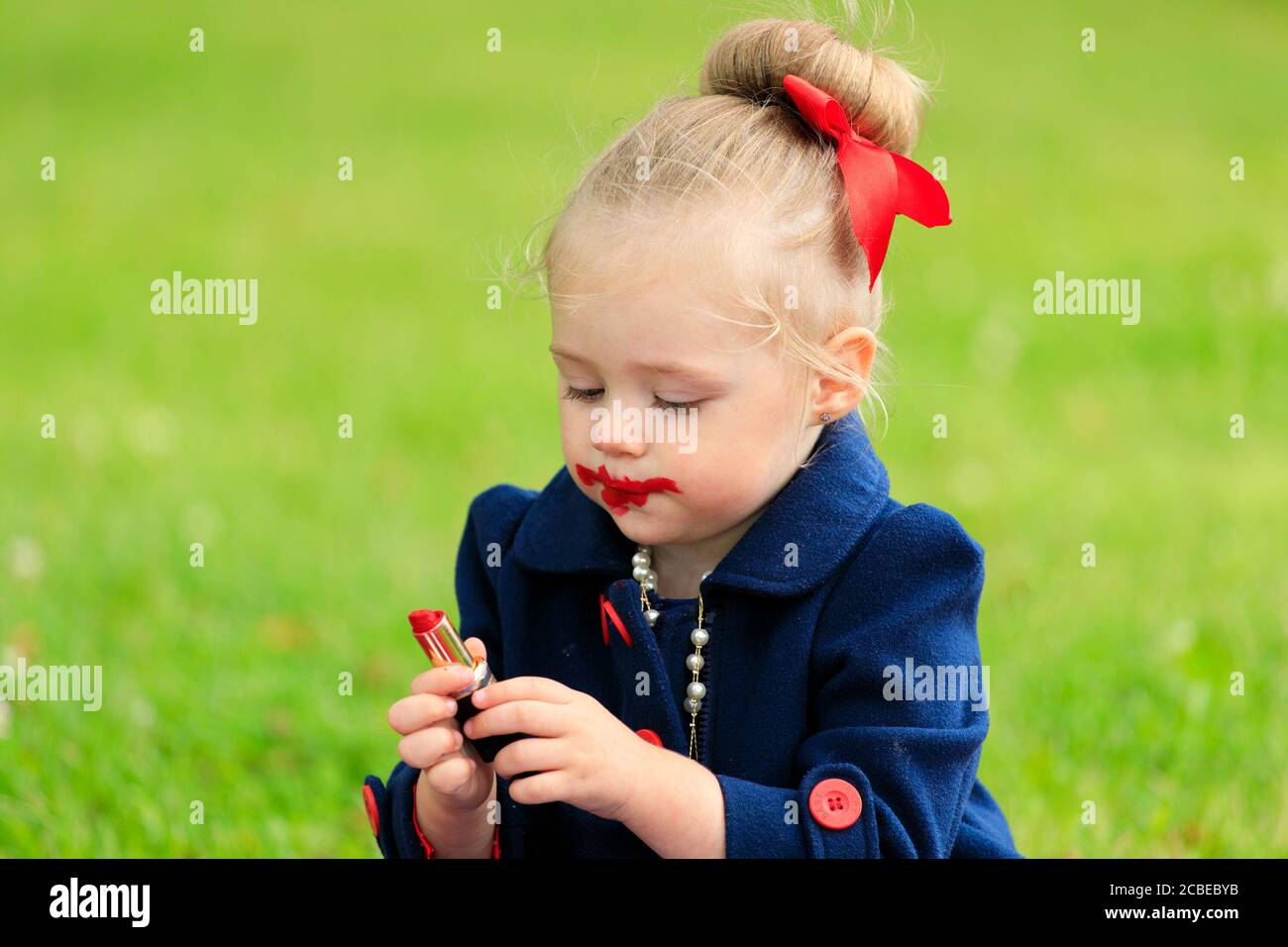 the child sits and paints his lips with red lipstick Stock Photo - Alamy