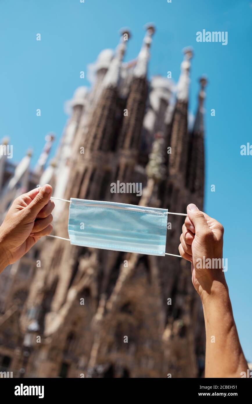 closeup of a man holding a blue face mask in front of La Sagrada ...