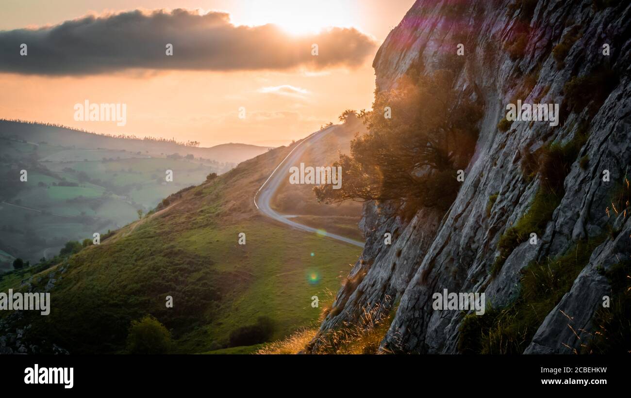 Beautiful shot of a cliff and green hills with a sunset sky background ...
