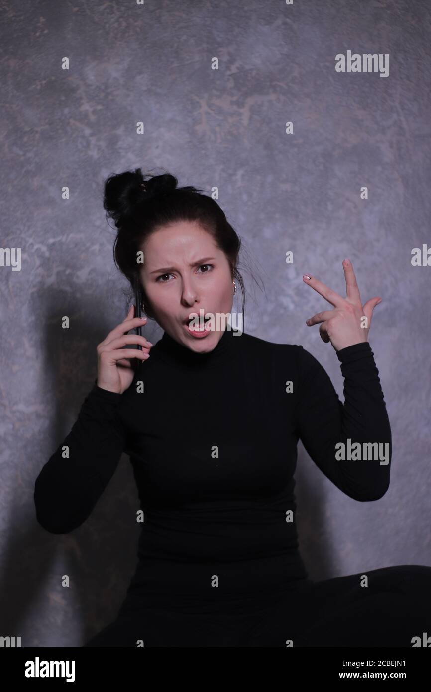 brunette girl in a black turtleneck indignantly talking on the phone ...