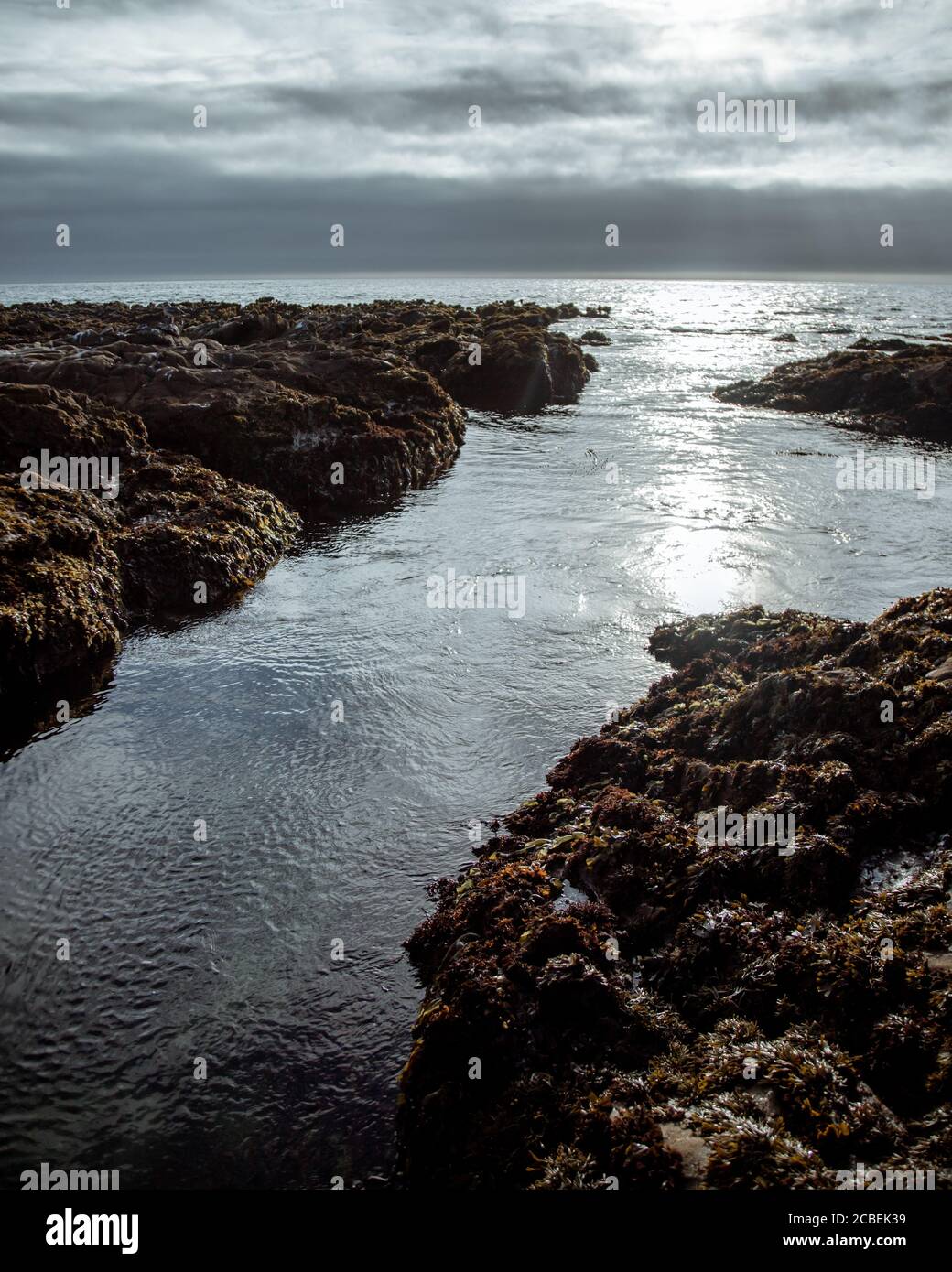 Cloudy ocean seen through rocks Stock Photo - Alamy