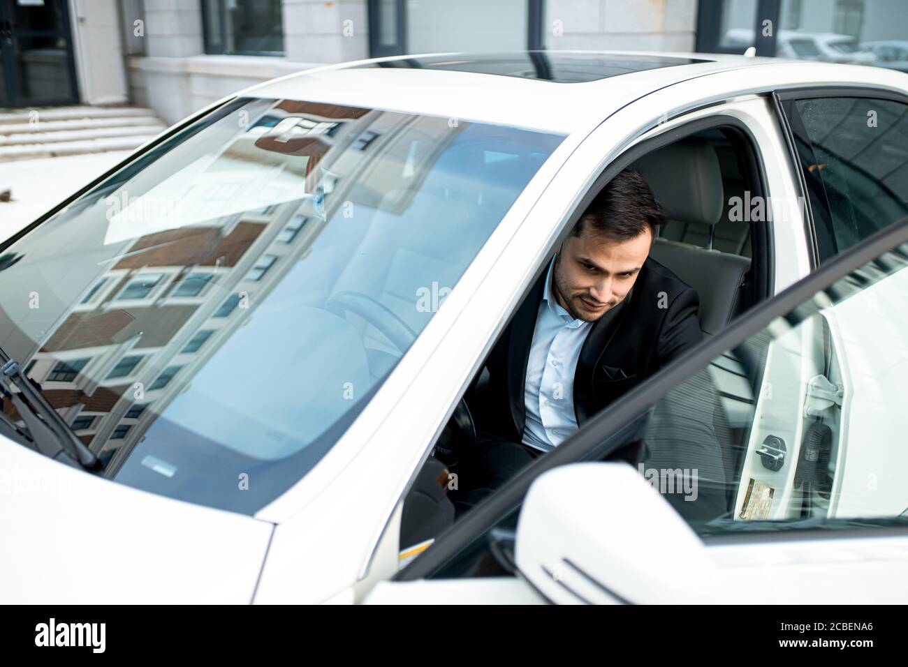 Handsome man wearing tuxedo getting out of executive car, white ...