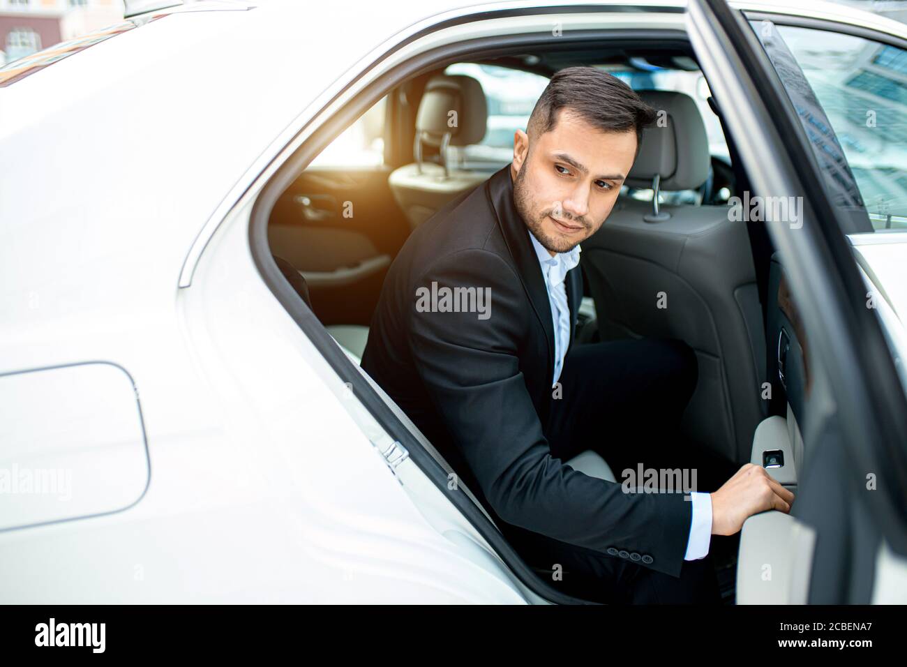 Confident young business male getting out from white executive car ...
