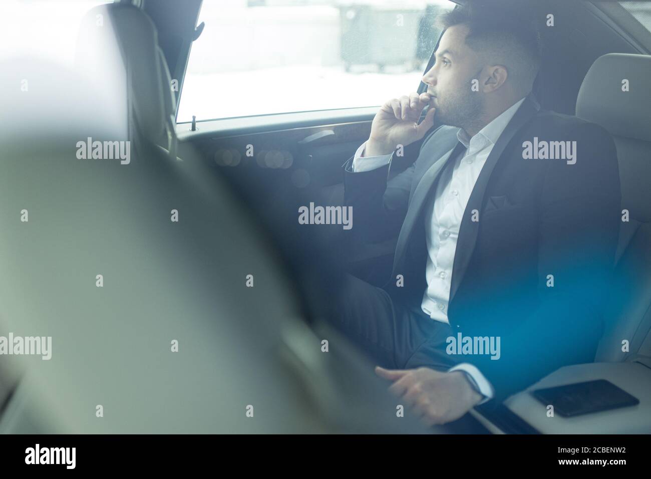 side view on dreamy man looking side in window inside of car, wearing ...