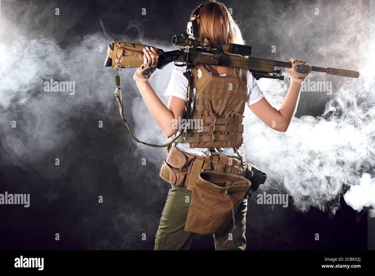 Backside of airsoft female shooter playing strikeball, sets her assault ...