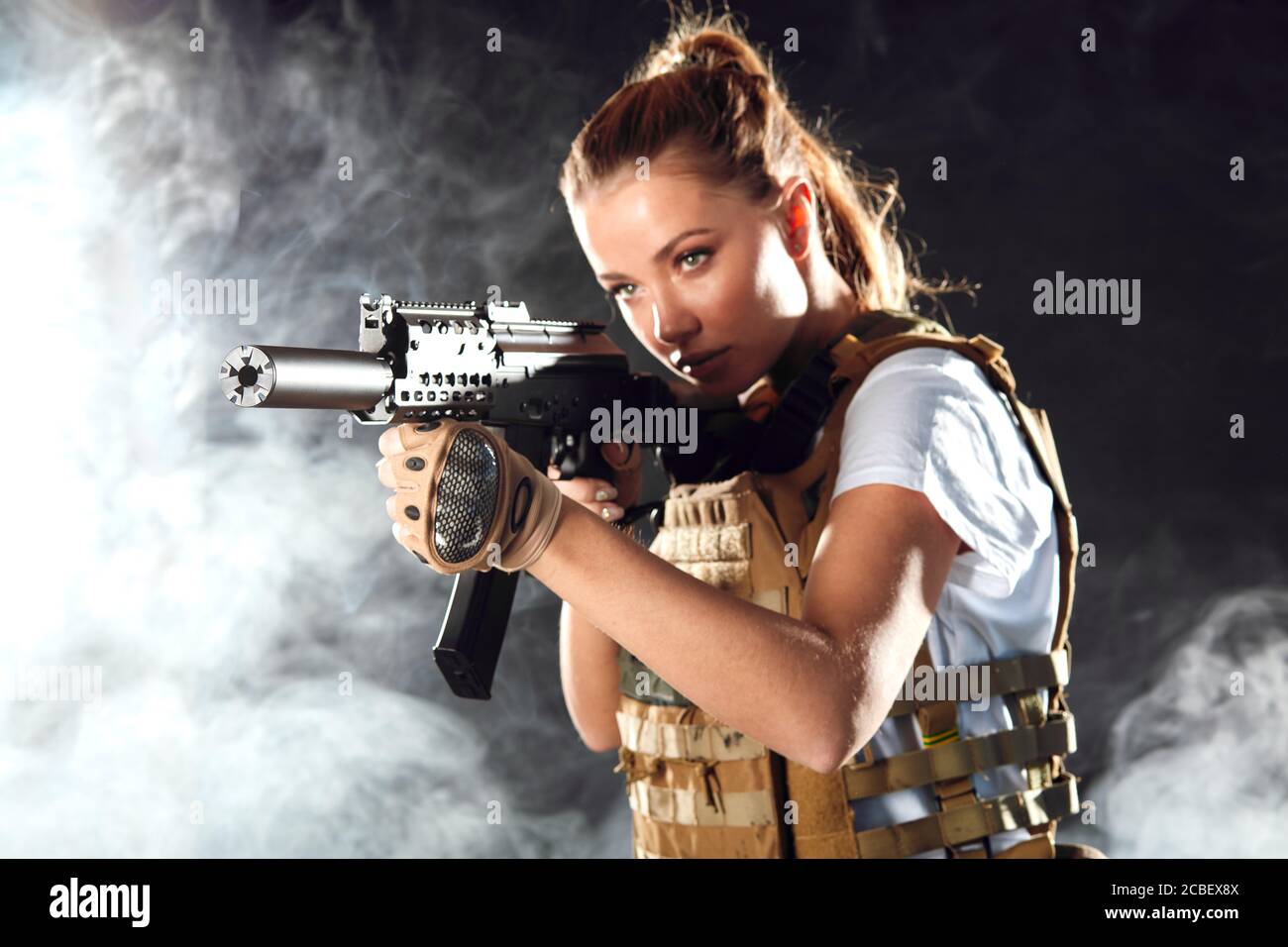 Portrait of a beautiful woman warrior in military outfit with firearm ...