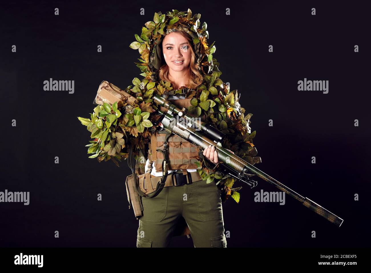 Woman soldier sniper in disguise poses with a sniper rifle and aims in ...