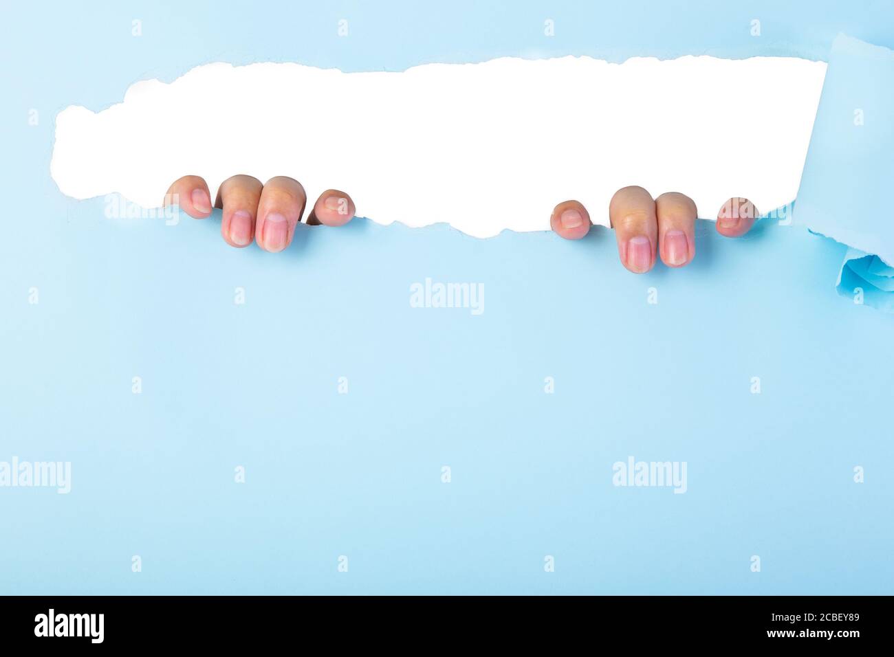 Person's hands tearing color paper background revealing copy space ...