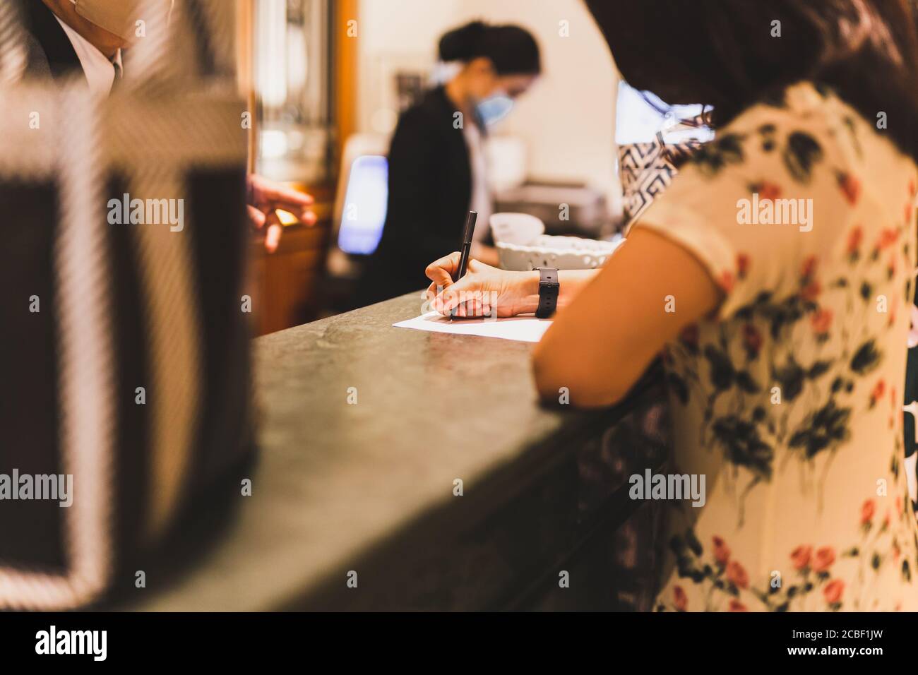 Woman client signing hotel contract paper at reception desk In face ...