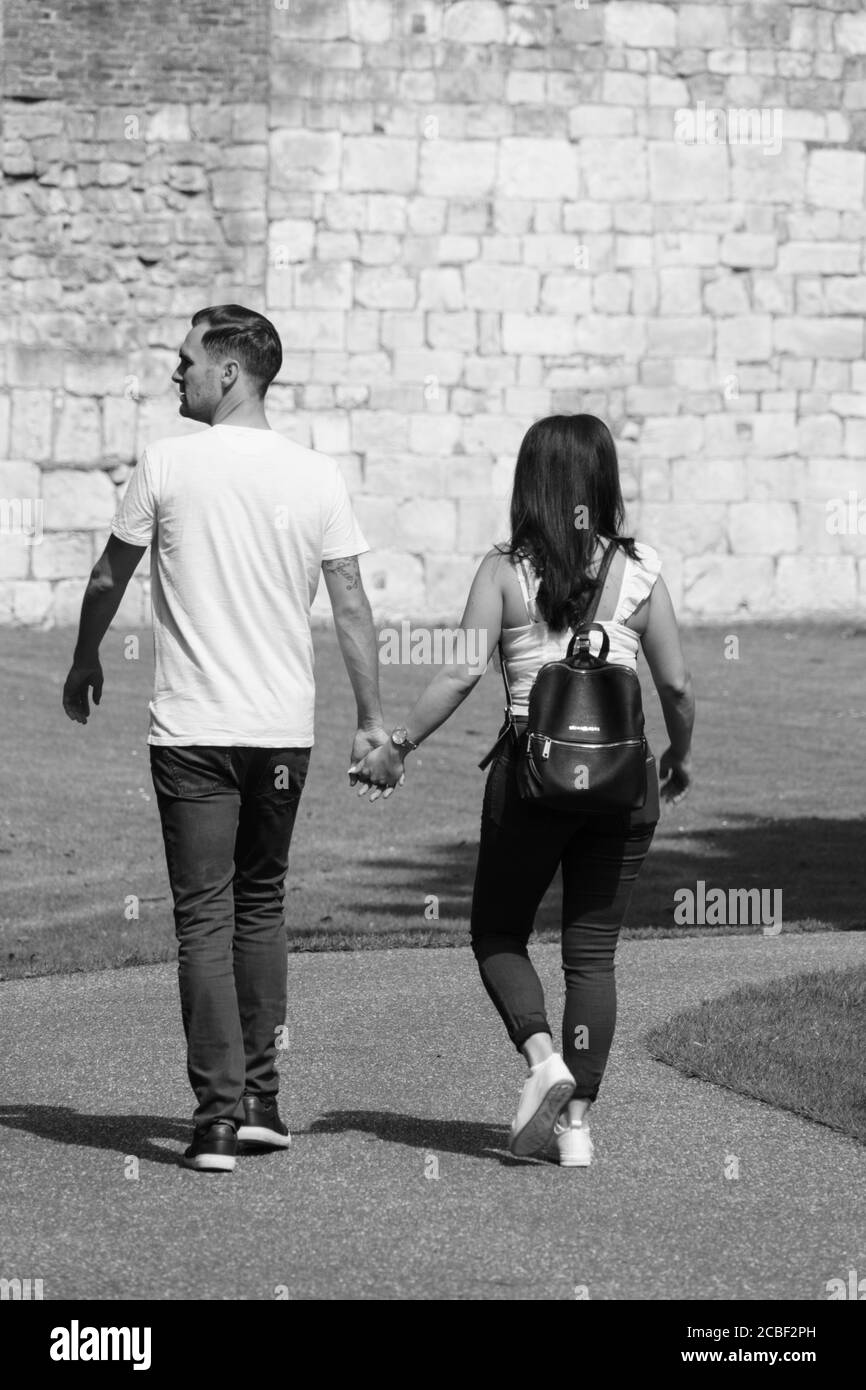 Laid-back man and woman walking hand and hand in a park in York, North ...