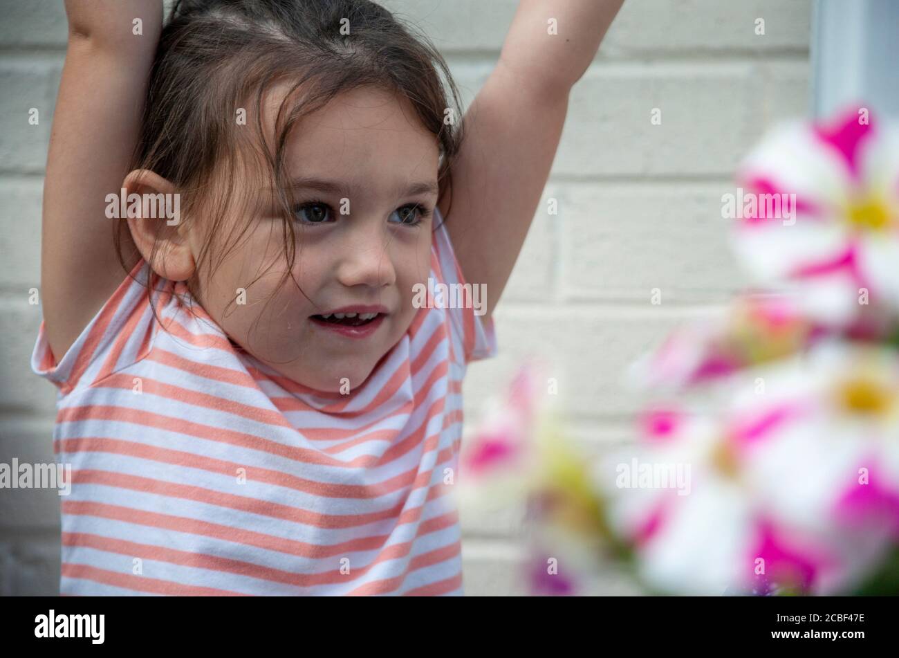 4 year old white girl, in stripey t-shirt and arms above her head ...