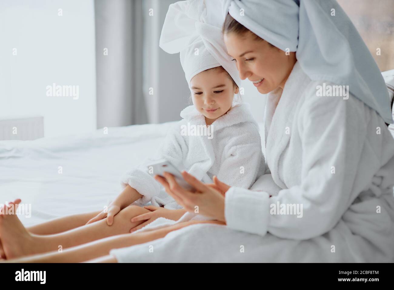 young modern beautiful woman wearing bathrobe and towel lie on bed with ...