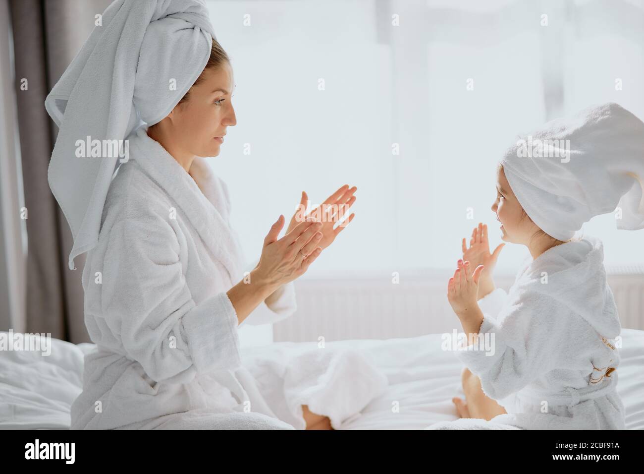 beautiful woman and her daughter sit clapping hands with each other ...