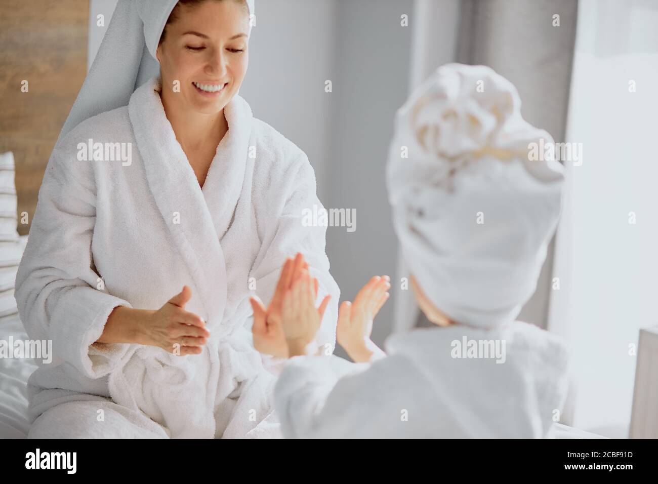 positive woman and her daughter sit clapping hands with each other ...