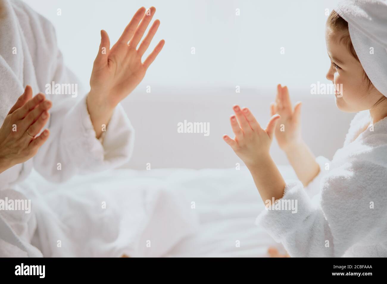 caucasian woman and little child daughter sit playing game of clapping ...