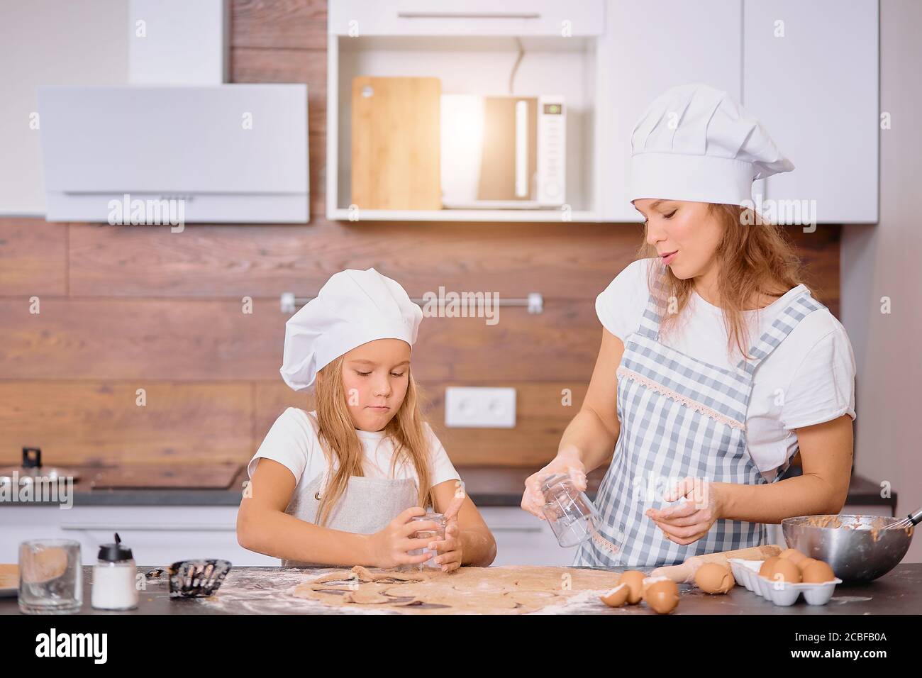caucasian woman and child girl together in kitchen, woman teach kid ...