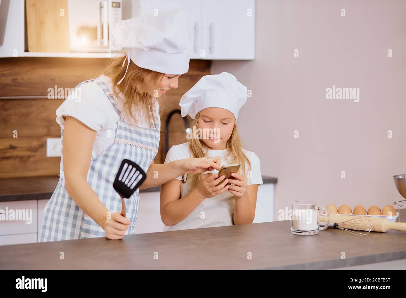 portrait of woman with kid girl thinking about baking something in ...