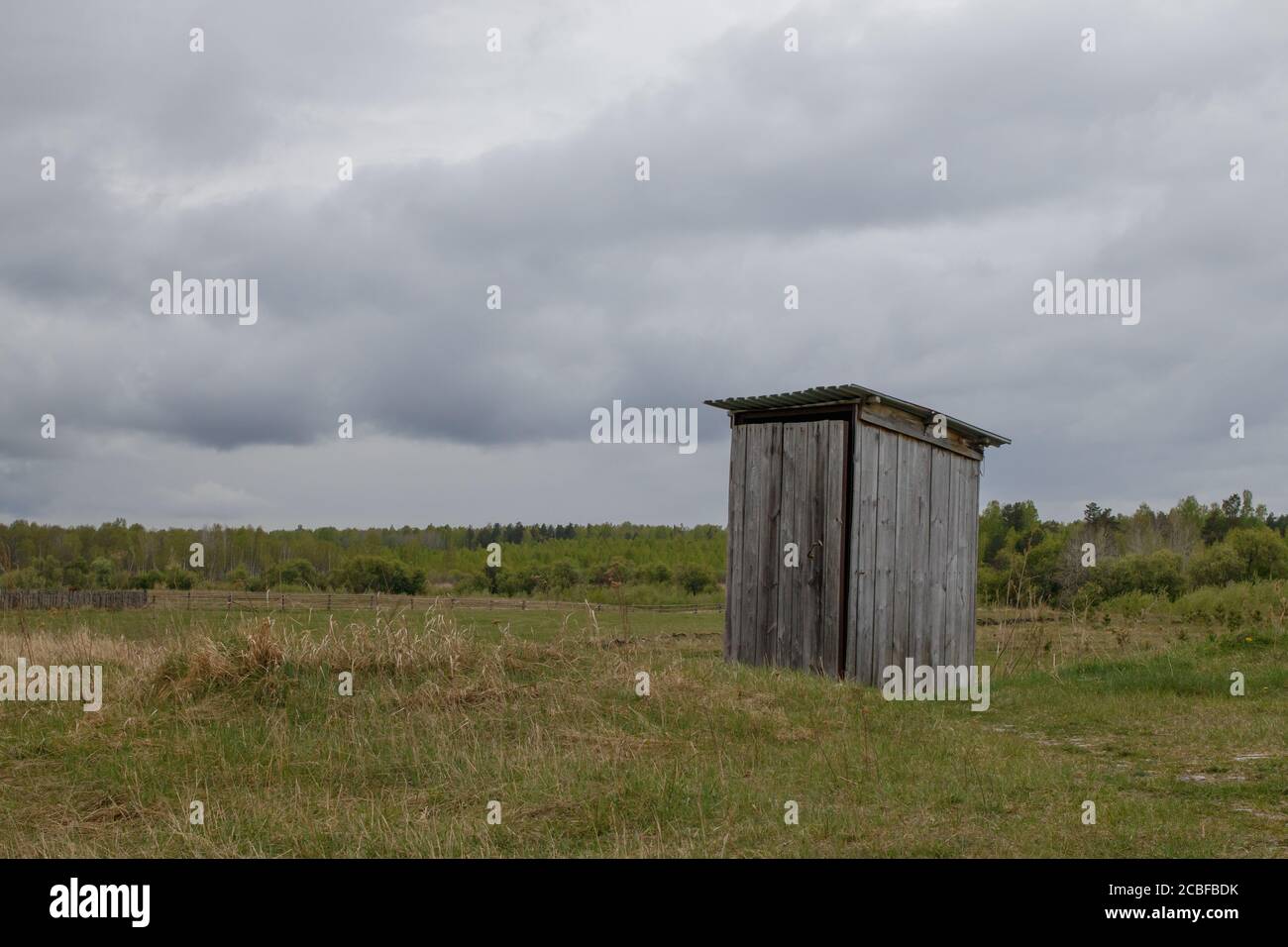 In the middle of the meadow stands a rustic public toilet made of ...