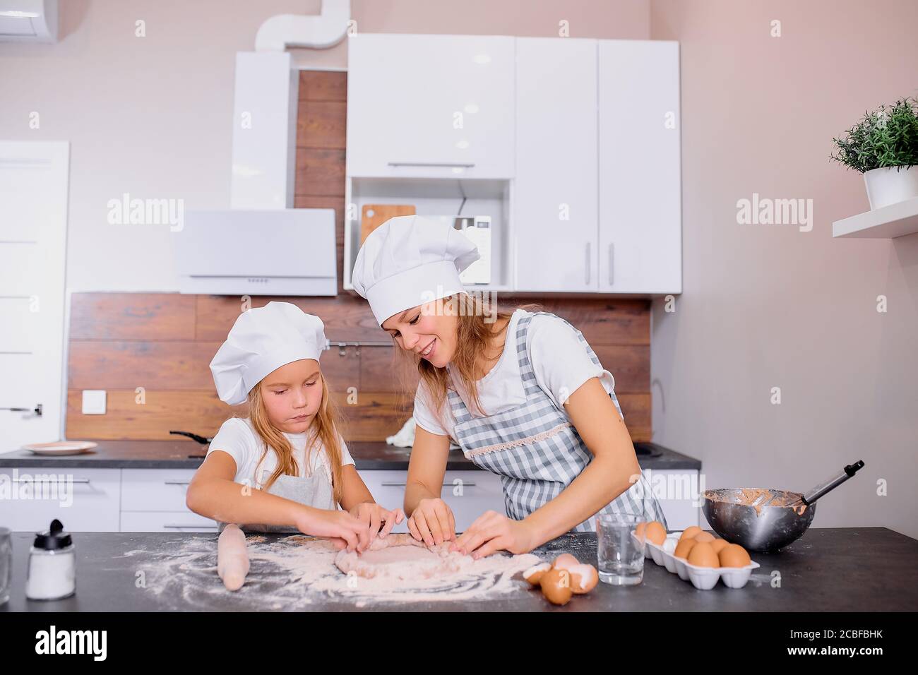 caucasian woman and child girl together in kitchen, woman teach kid ...