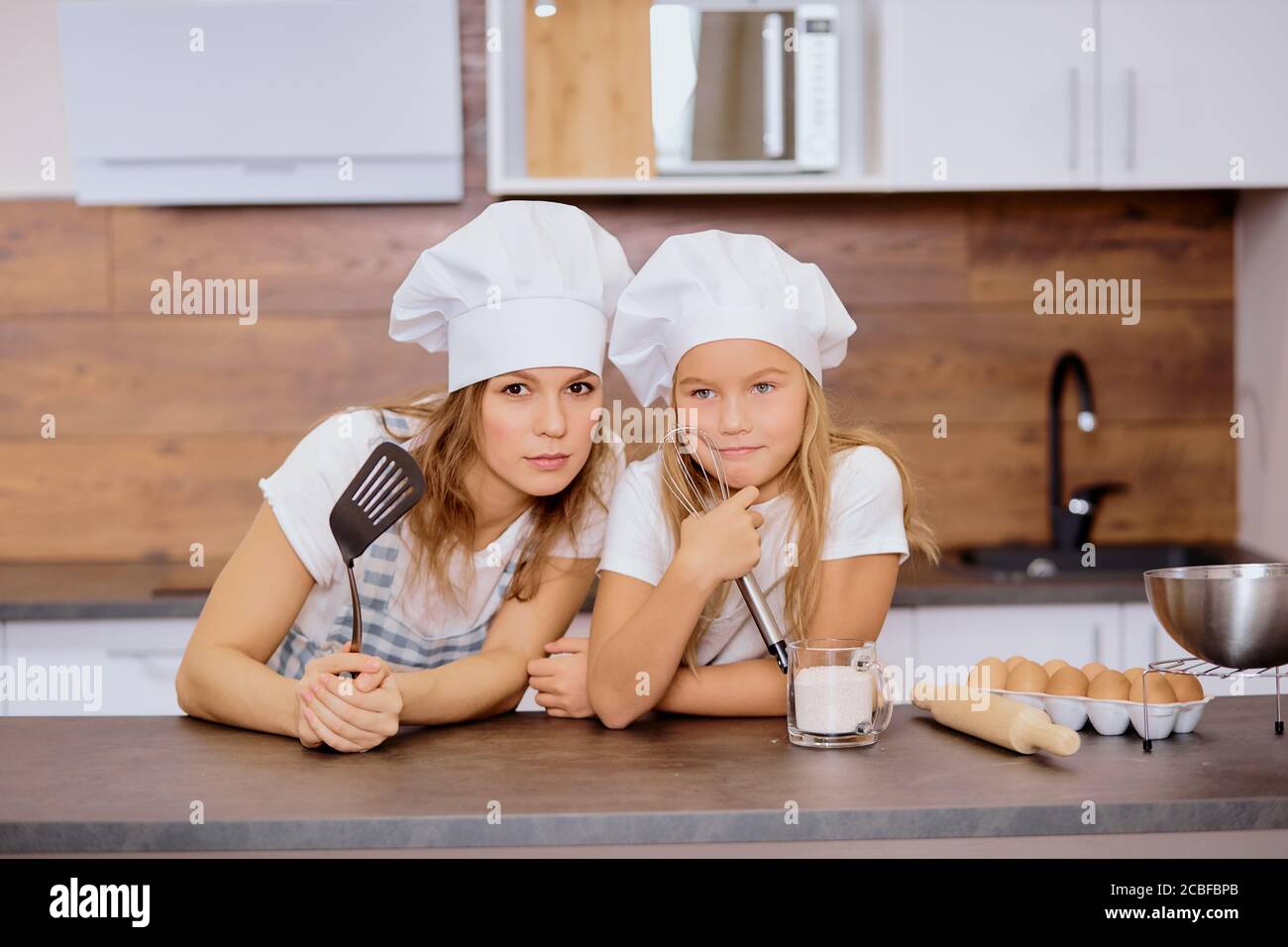 cunning adult and kid girl think about future baking, cooking together ...