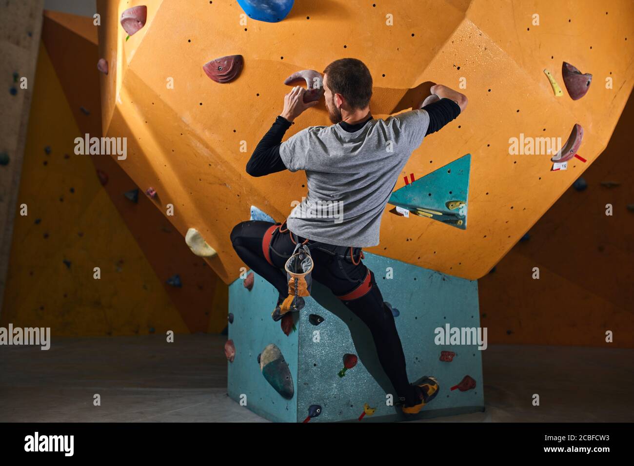 Rear view of powerful physically challenged male boulderer climbing at ...
