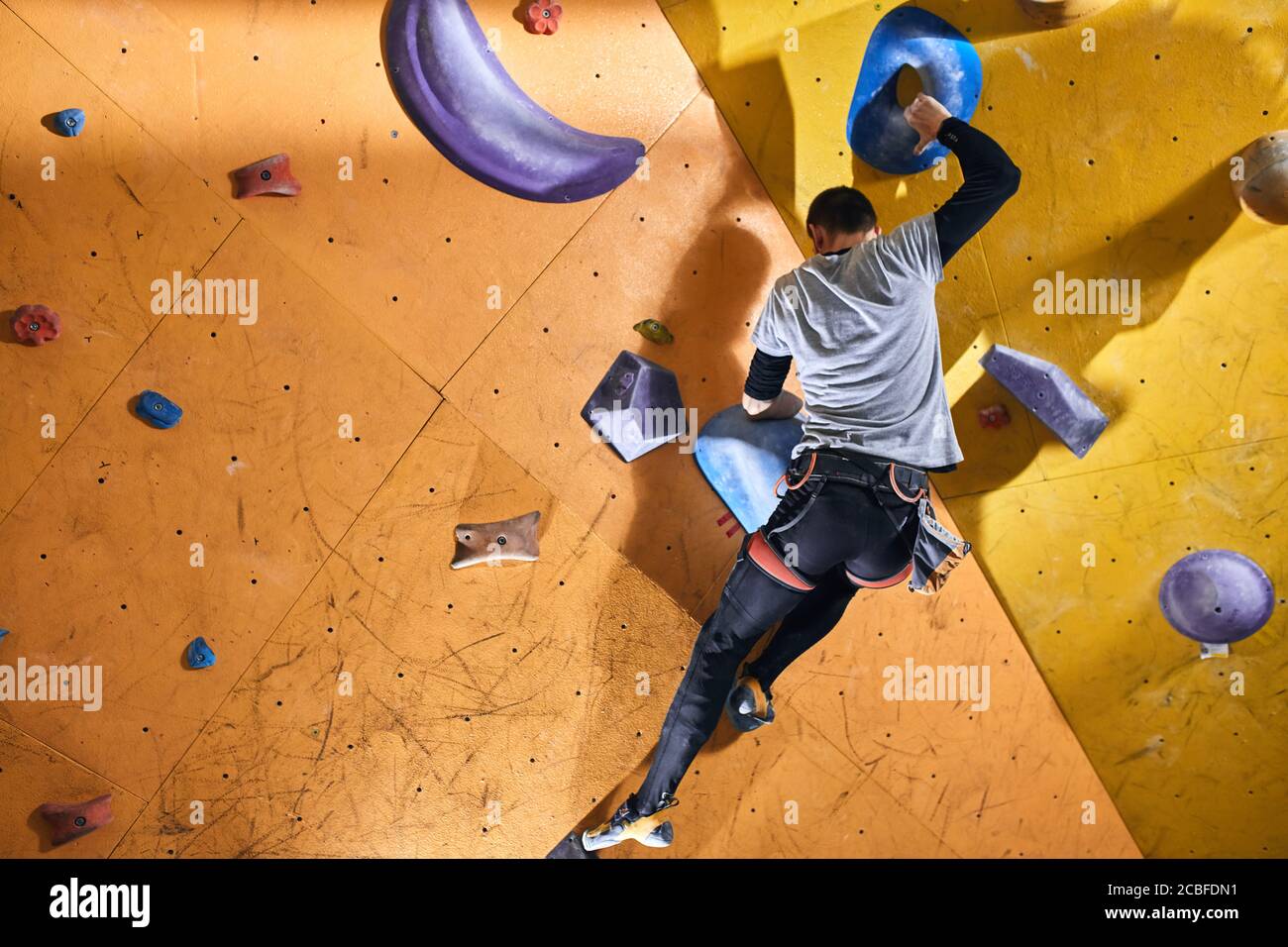 Rare view of powerful physically challenged man climbing yellow wall ...