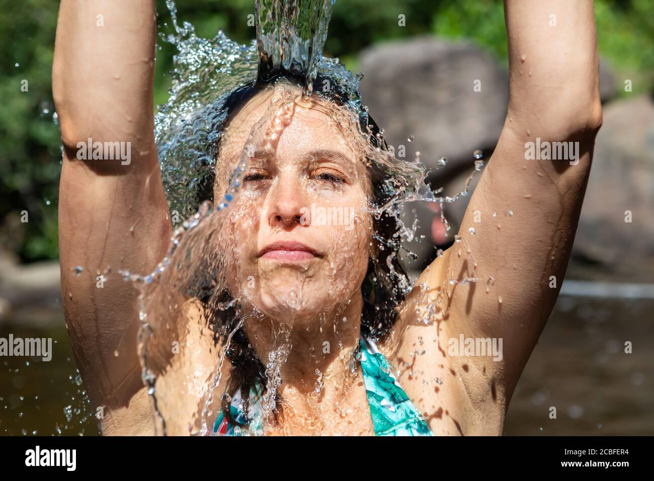 Close up shot of the face of a young woman with her arms up, pouring ...