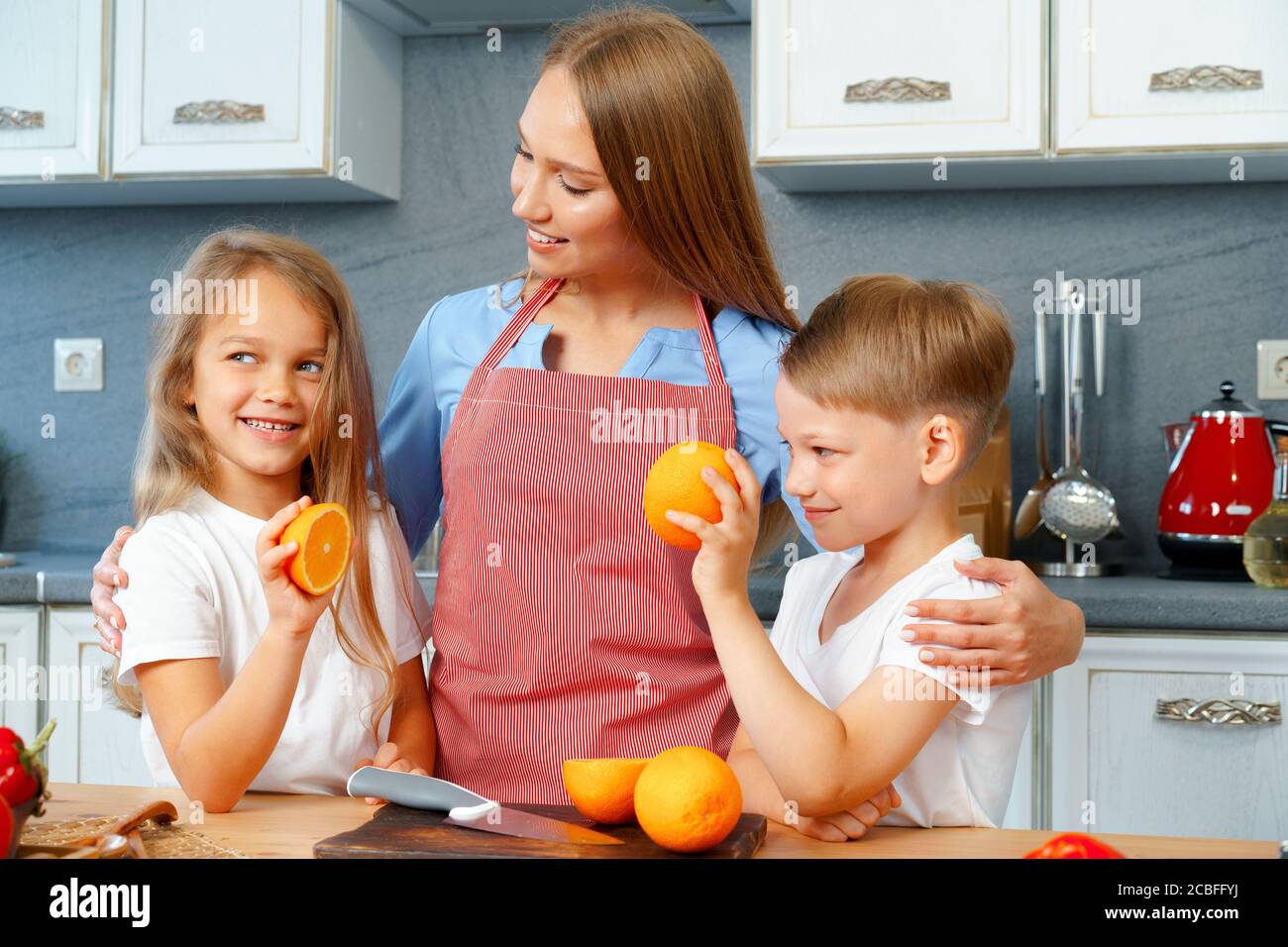 Mother cooking with her children in kitchen Stock Photo - Alamy