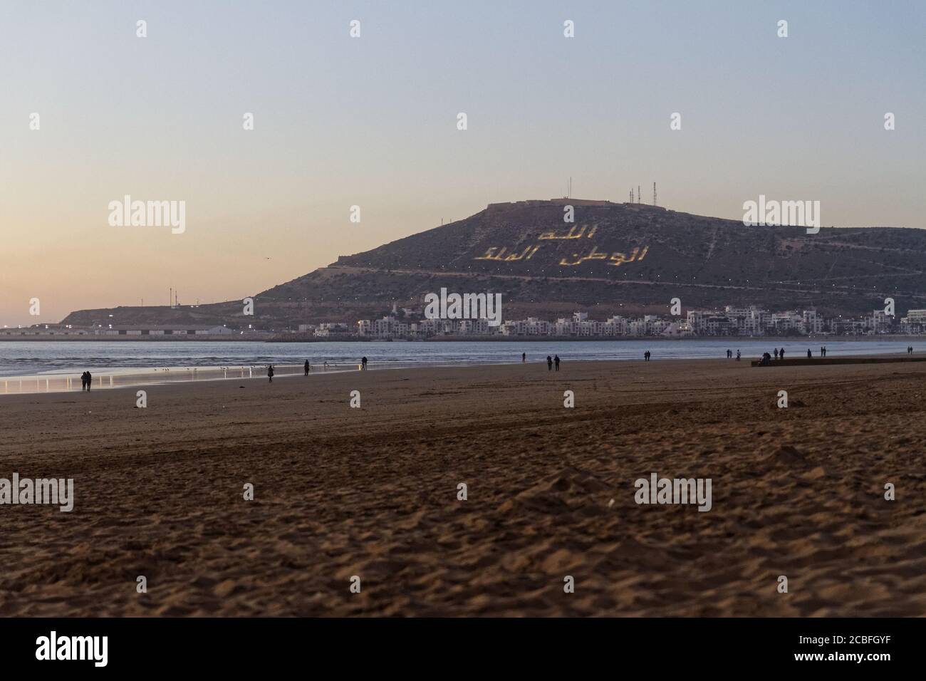 Agadir, Morocco beach with Moroccan motto on the mountain. Writing on ...