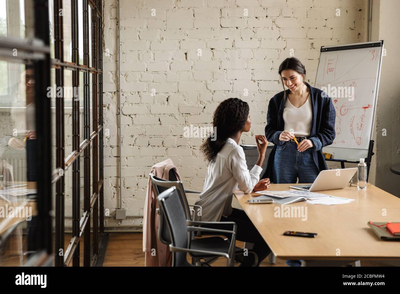 Two attractive smart multiethnic women entrepreneurs working over new ...