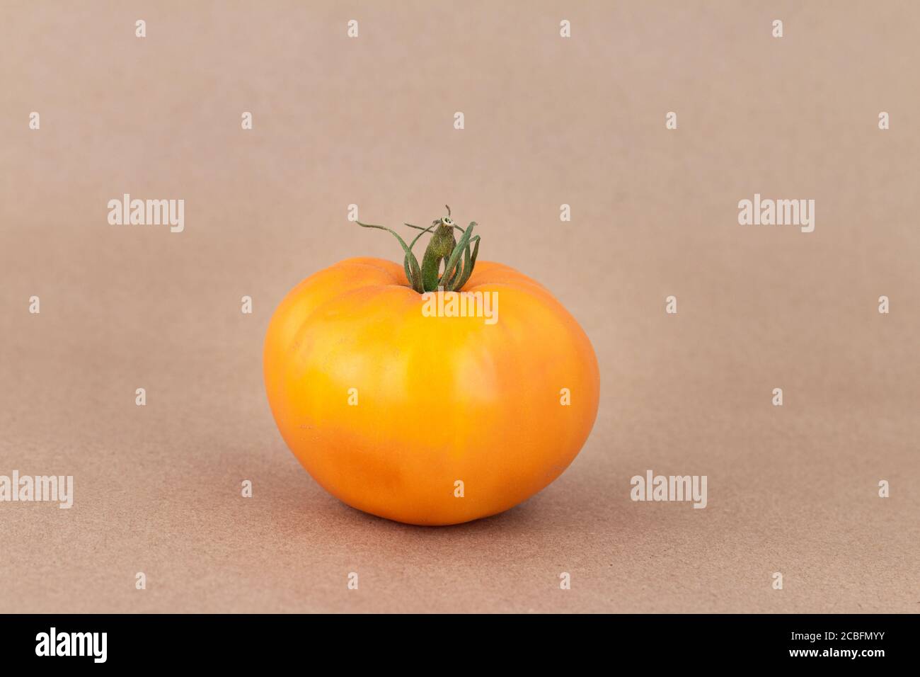 Yellow big tomato isolated on beige color background Stock Photo - Alamy