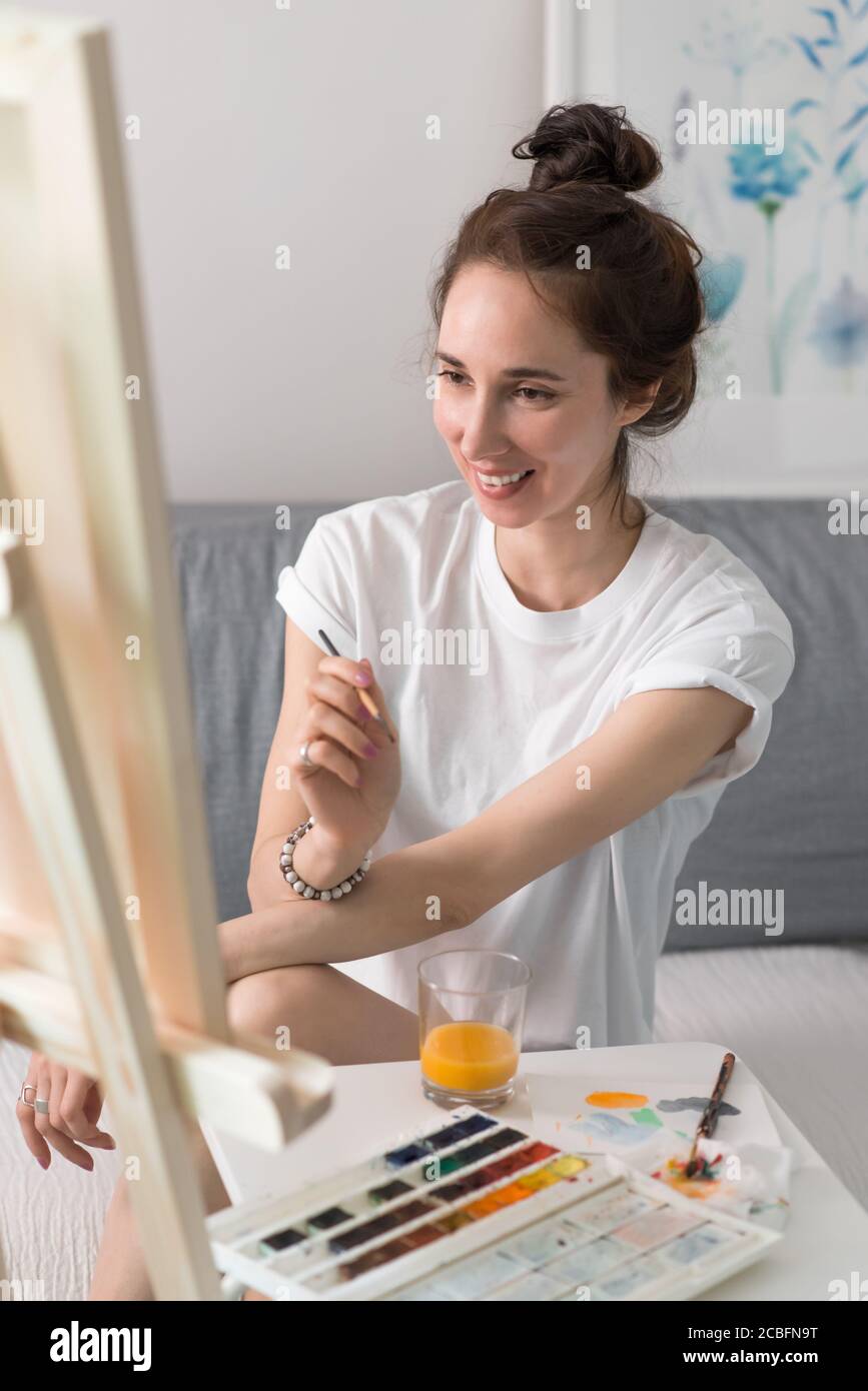 Happy and beautiful woman artist, smiling and laughing, at home on the ...