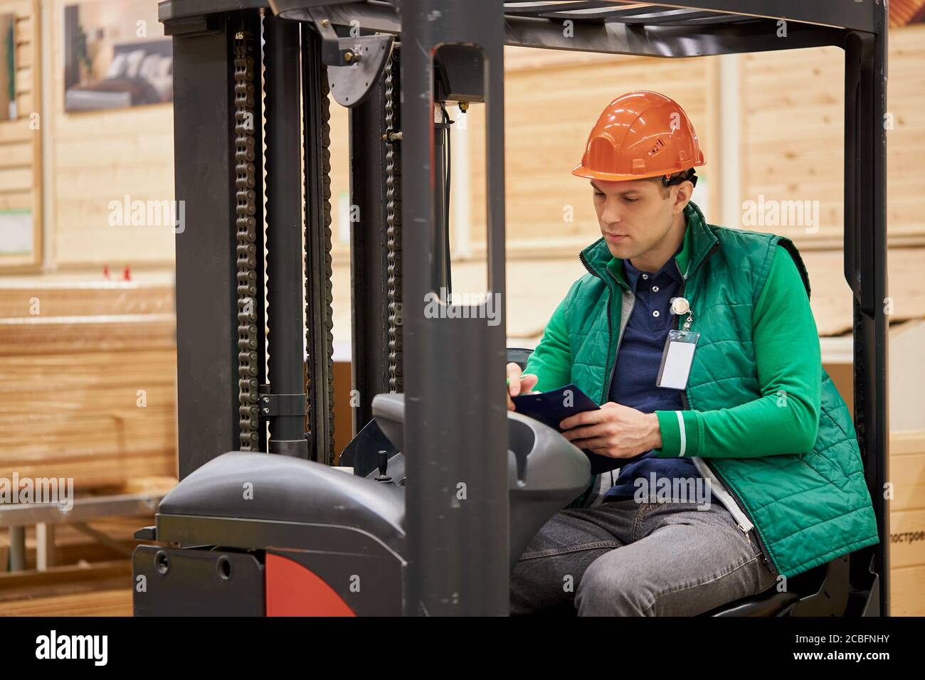serious warehouse worker sit inside of machine in cab. man in ...