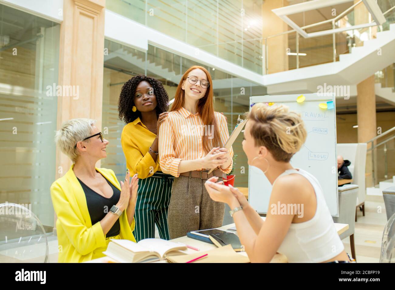 attractive happy female employees greeting their new ginger colleague ...