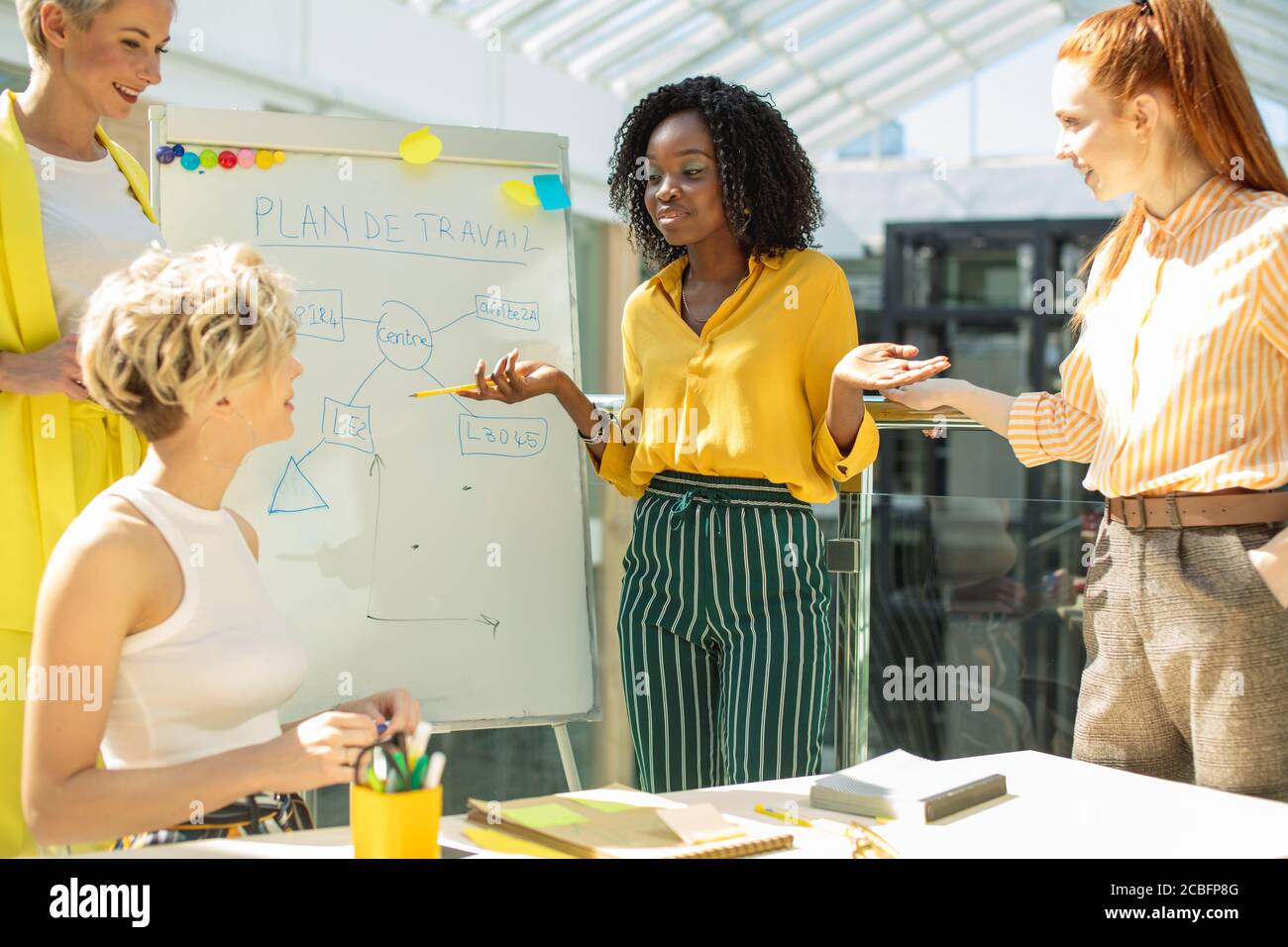 Afro stylish woman with a pen in her hand teaching her colleagues the ...